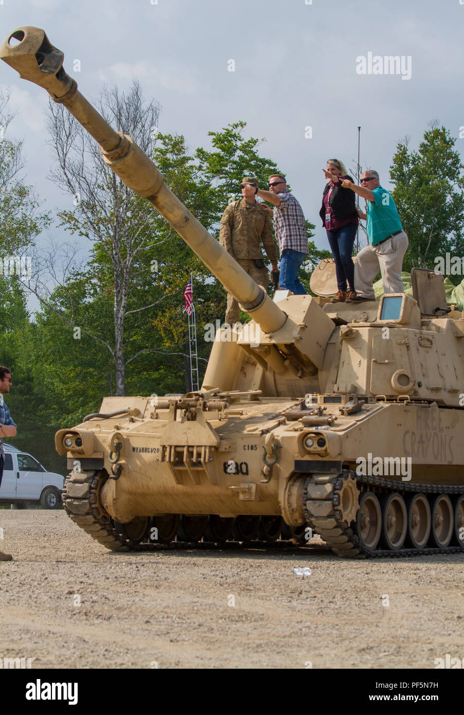 A trio of Distinguished Visitors pose for a picture on top of an M109 ...