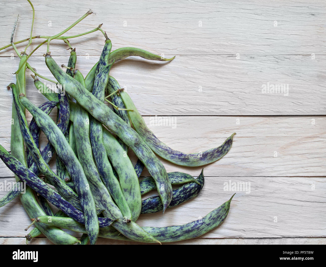 Uncleaned raw string beans lie on a plank background Stock Photo - Alamy