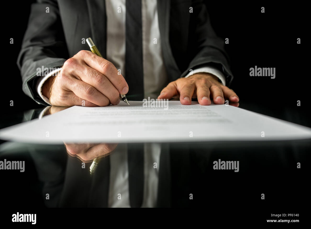 Front view of businessman signing important legal document on black ...