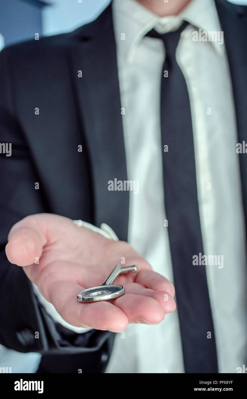 Front view of a businessman offering a key Stock Photo - Alamy