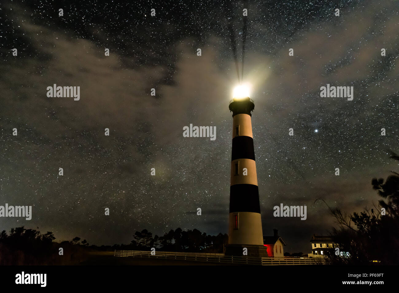 Lighthouse on the outer banks shining brightly in the night in front of ...