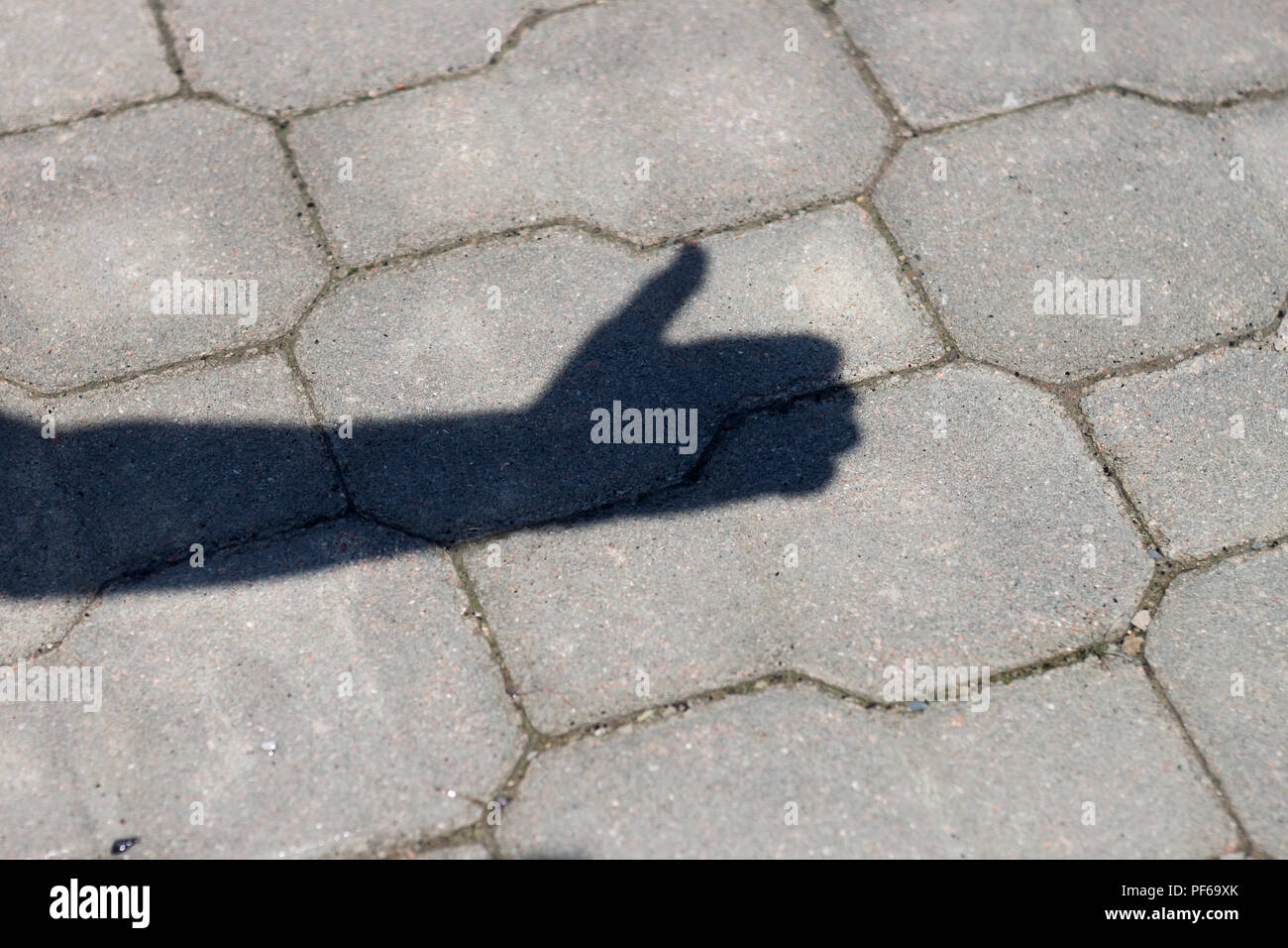 Close-up shot of shadow silhouette of human arm and hand with thumb-up ...