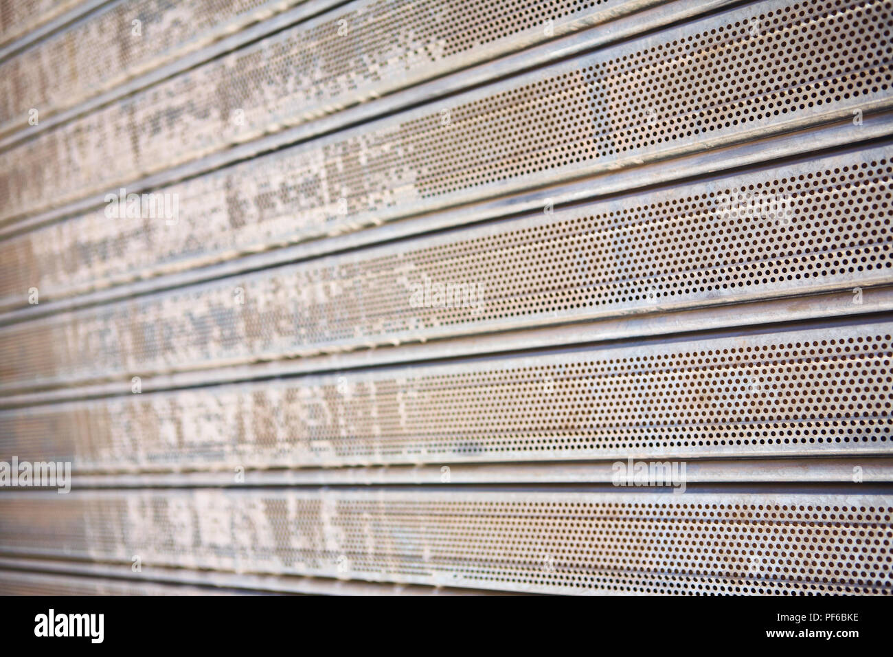 Grungy rusty worn looking shop security roller shutter with a mesh of ...