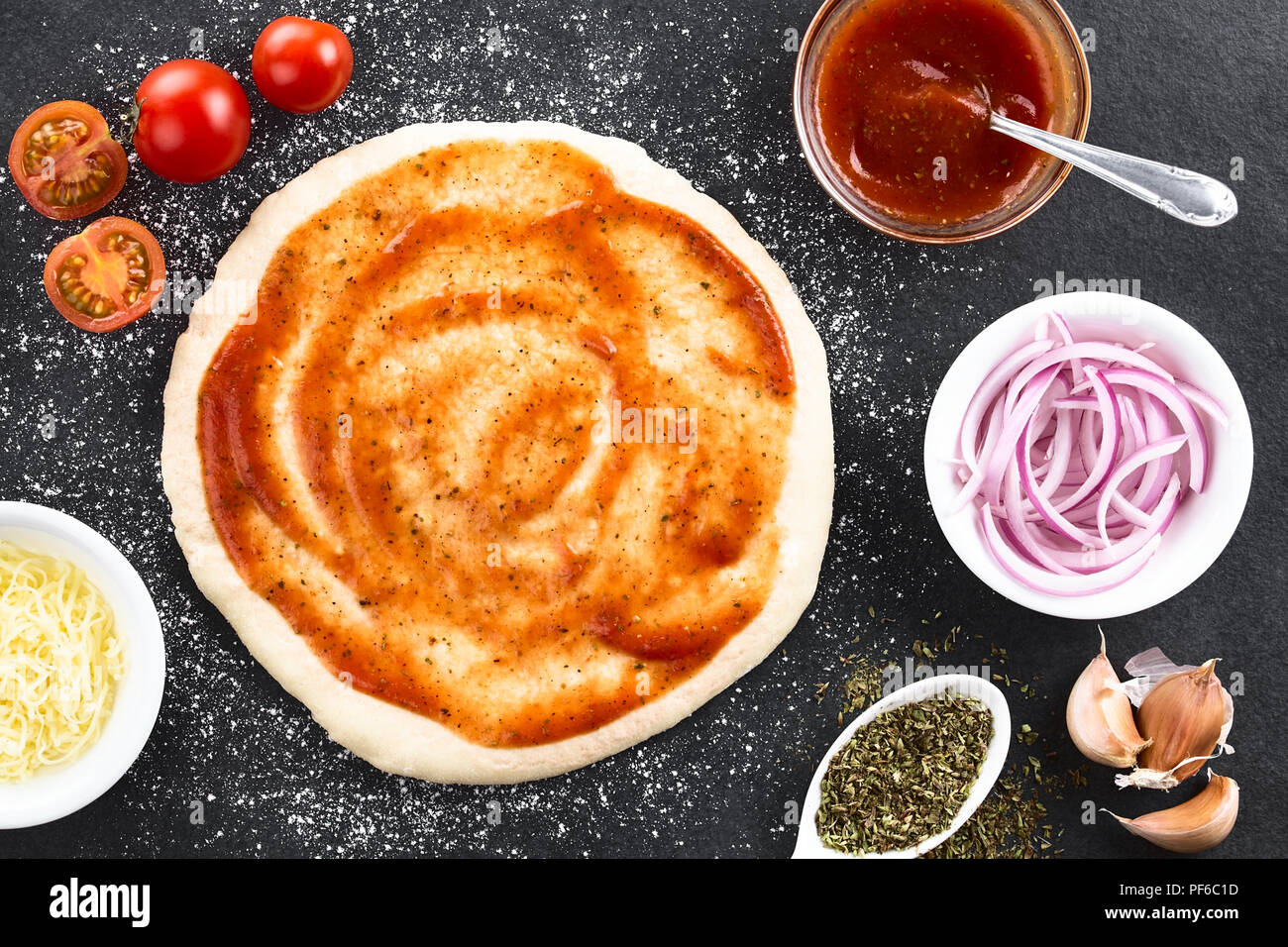 Preparing homemade pizza, ingredients (tomato sauce, garlic, onion ...