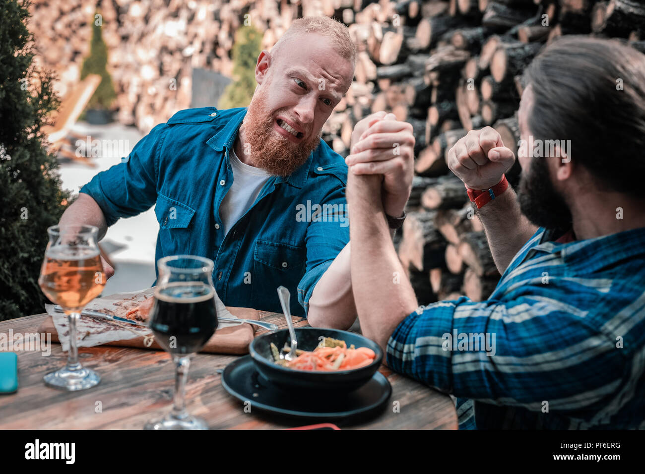 Bearded men arm wrestling while drinking beer together Stock Photo - Alamy