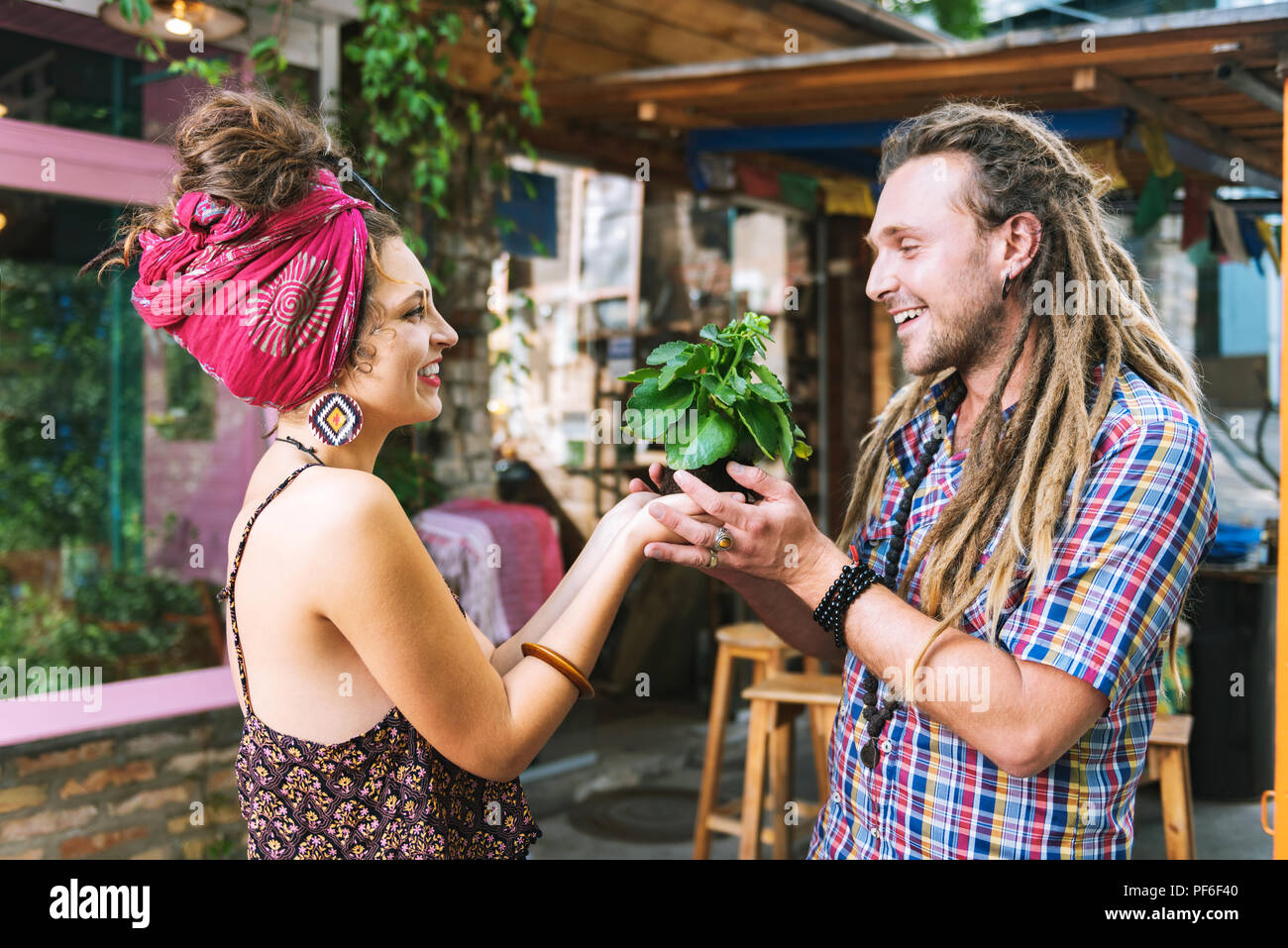 Two beaming happy hippies feeling nice growing little plant Stock Photo ...