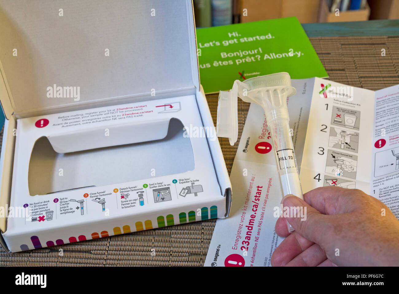 23andme home genetic testing kit. Person holding saliva collection tube ...