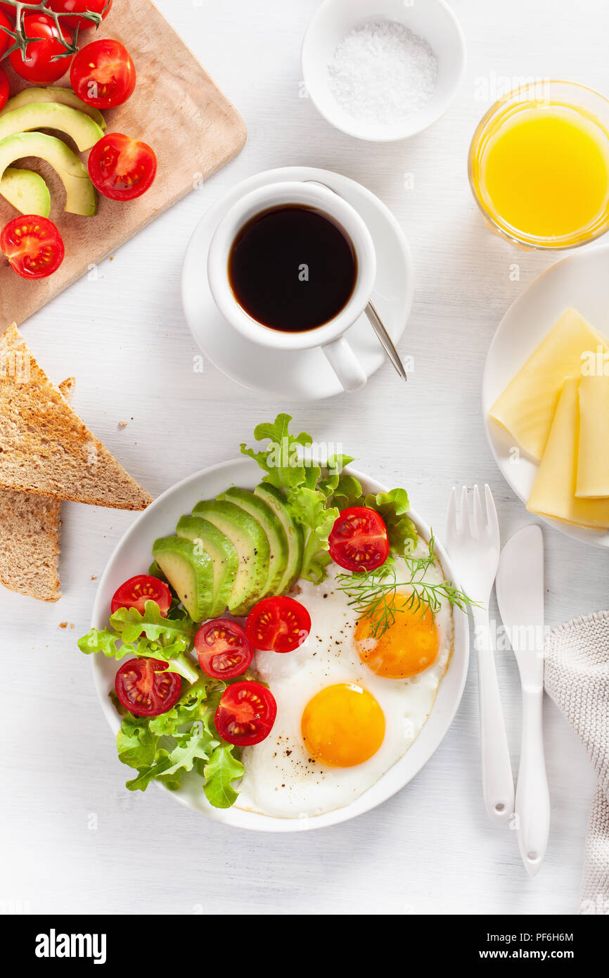 healthy breakfast flat lay. fried eggs, avocado, tomato, toasts and ...