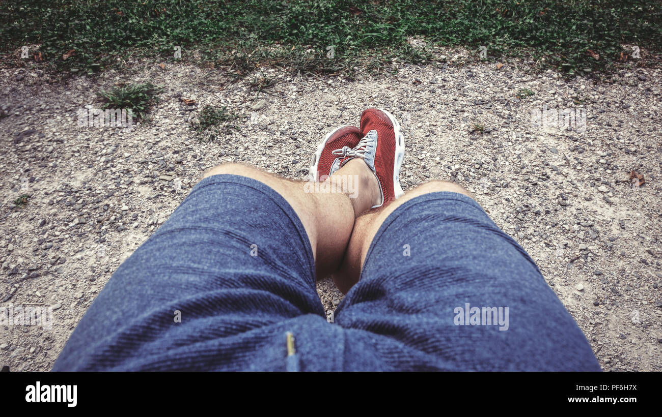 The legs of a sitting man in shorts and sneakers. View from above Stock ...