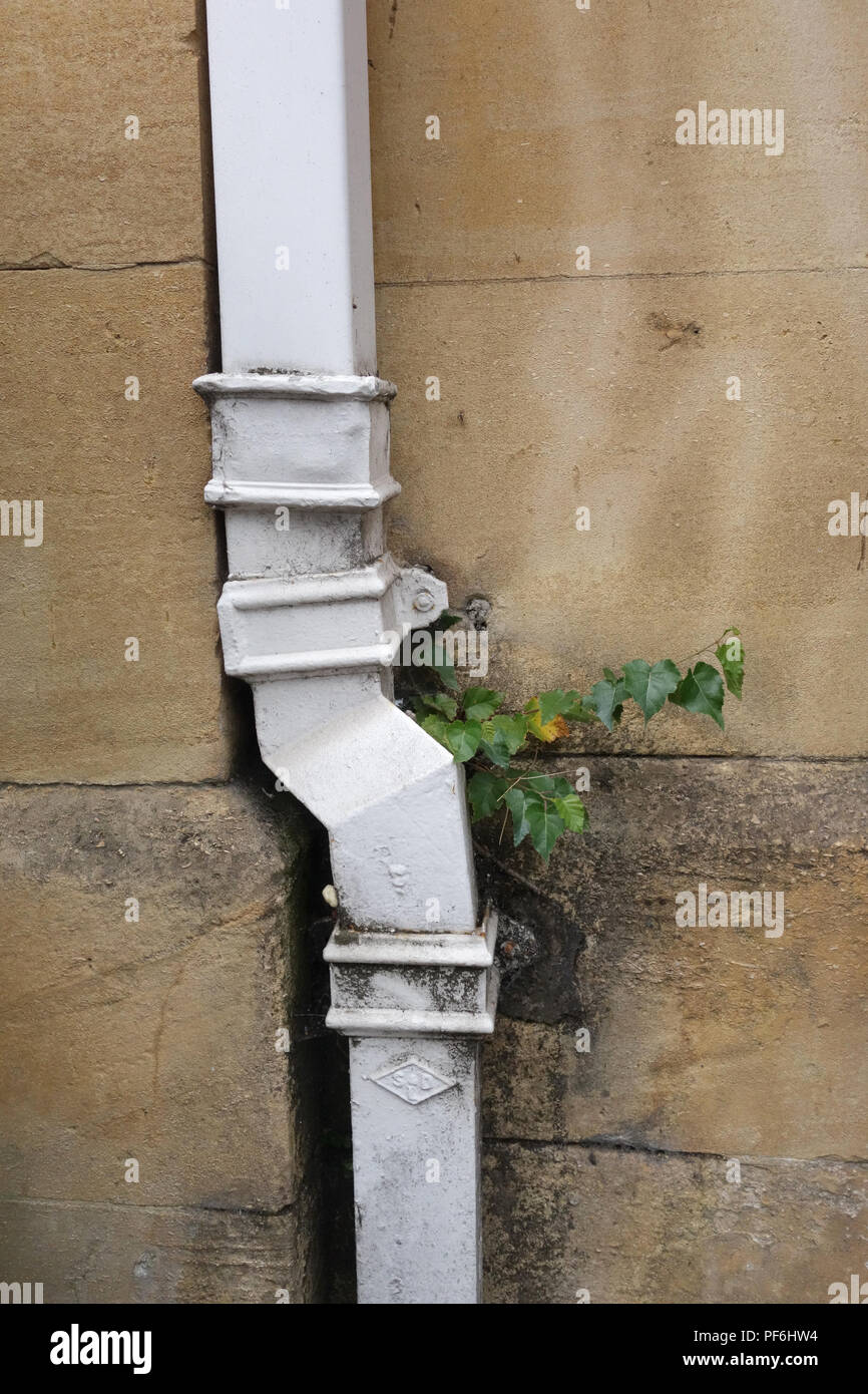 Handmade metal rainwater fall pipe cut and shaped to fit around a stone ...