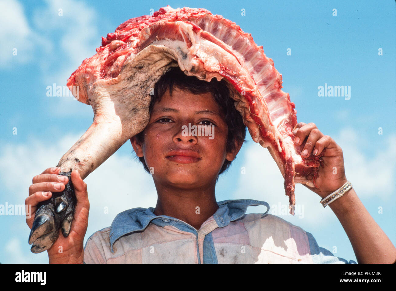 A boy holding a large piece of raw meat above their head against a ...