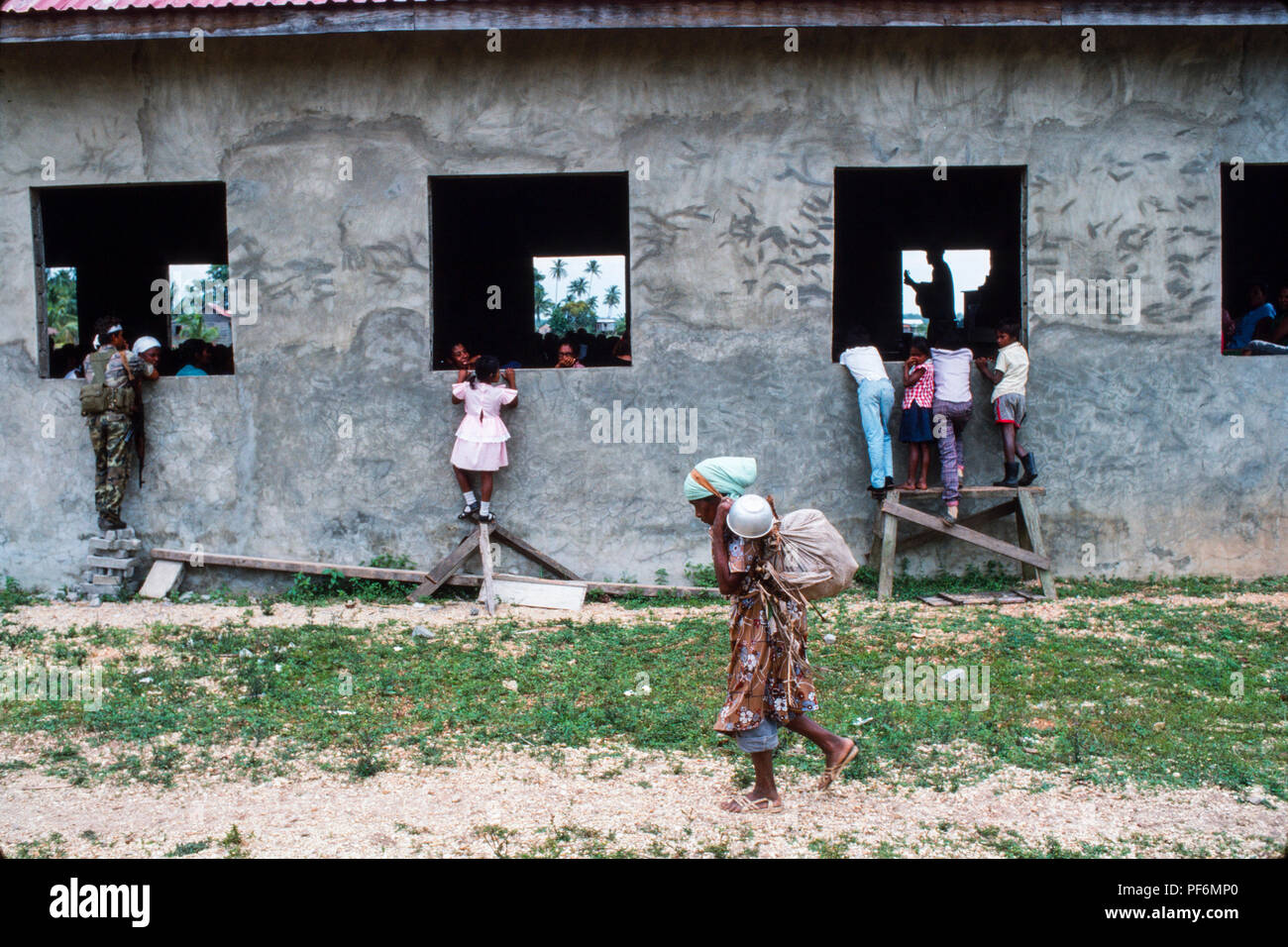 Children peer through windows of a building while a woman walks by ...
