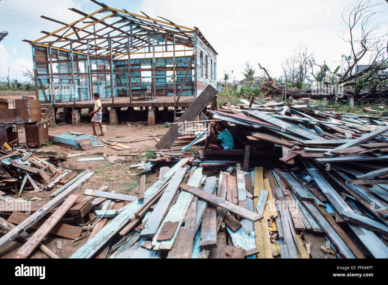A damaged structure and debris after a storm with two people in the ...