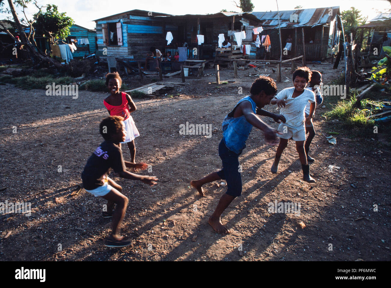 Children play joyfully outdoors in a rural village with wooden houses ...