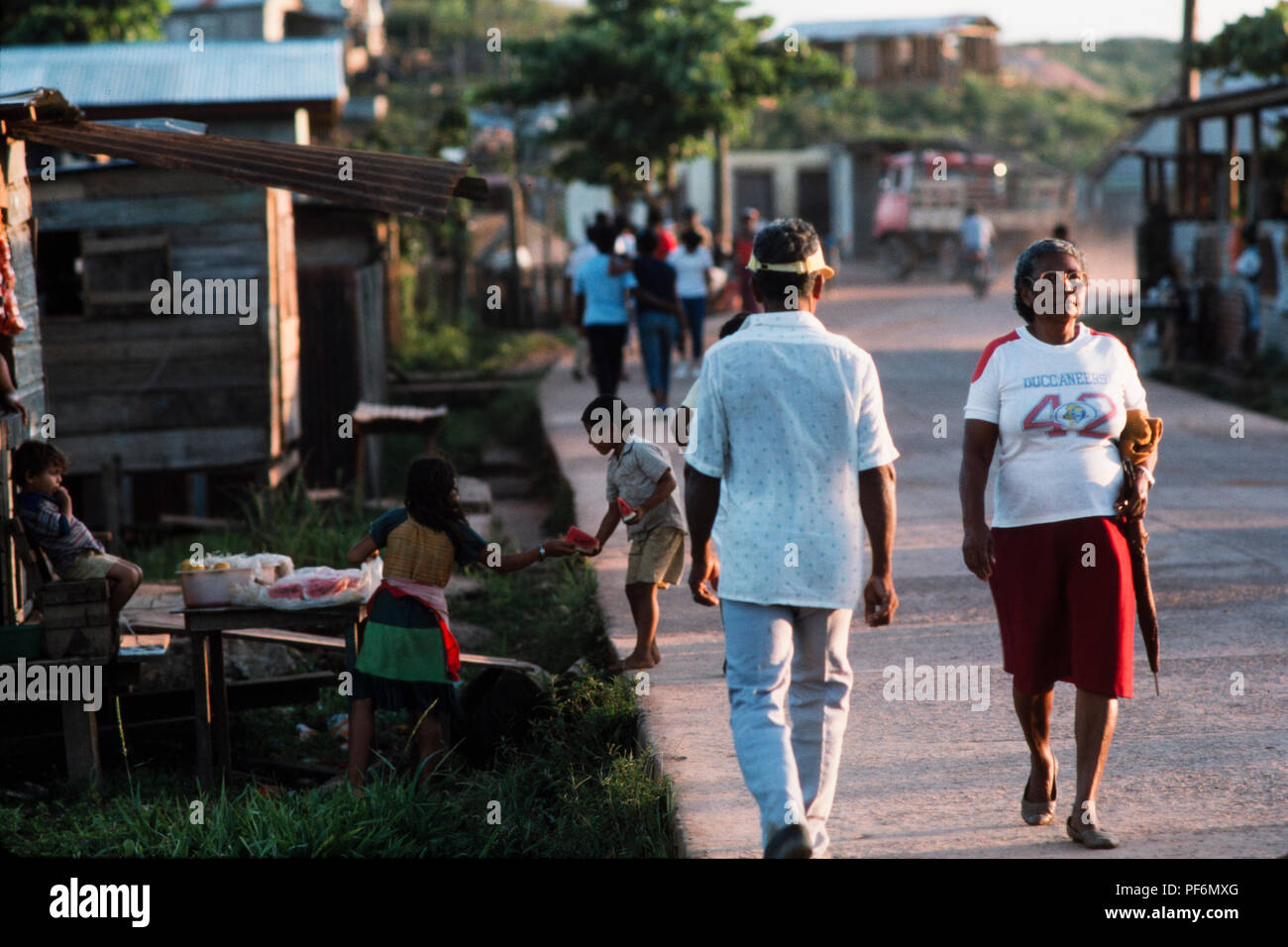 A street scene depicting people walking and children playing in a rural ...