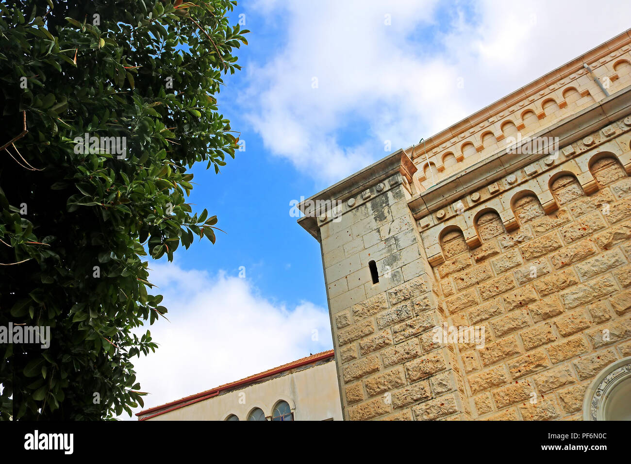Wall of Joseph Church, foliage of tree and blue sky in Nazareth, Israel ...