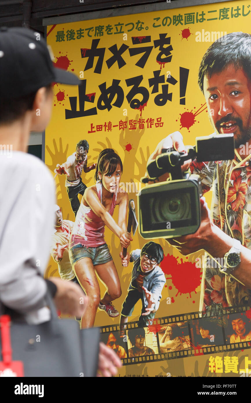 A man walks past a poster of the film One Cut of the Dead (Japanese ...