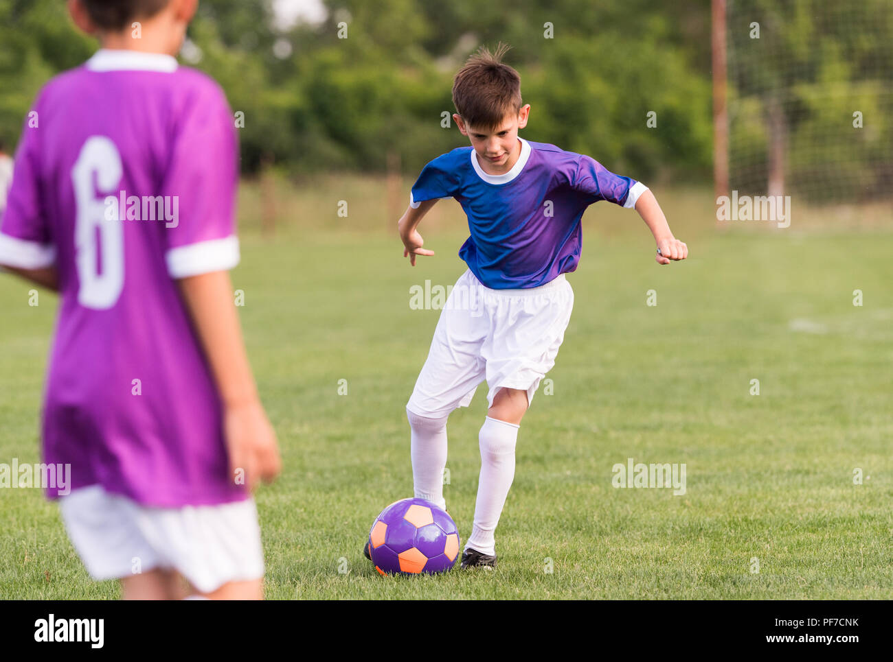 Boy kicking football on the sports field during soccer match Stock ...