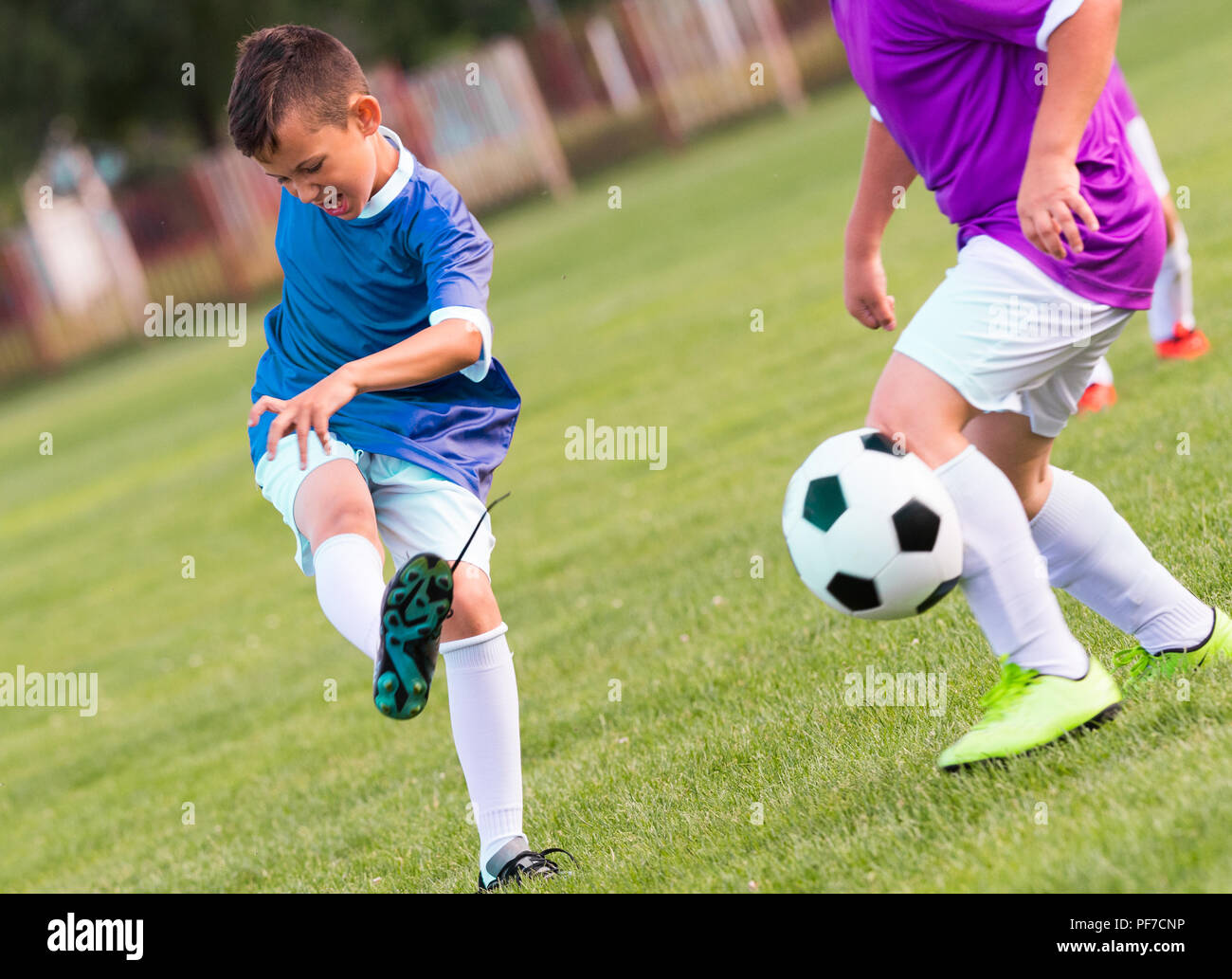 Boy kicking football on the sports field during soccer match Stock ...