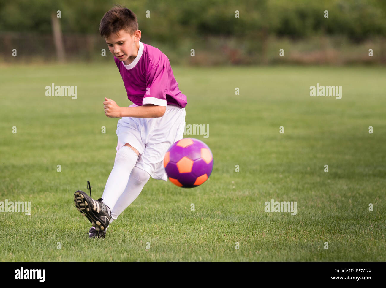 Boy kicking football on the sports field during soccer match Stock ...