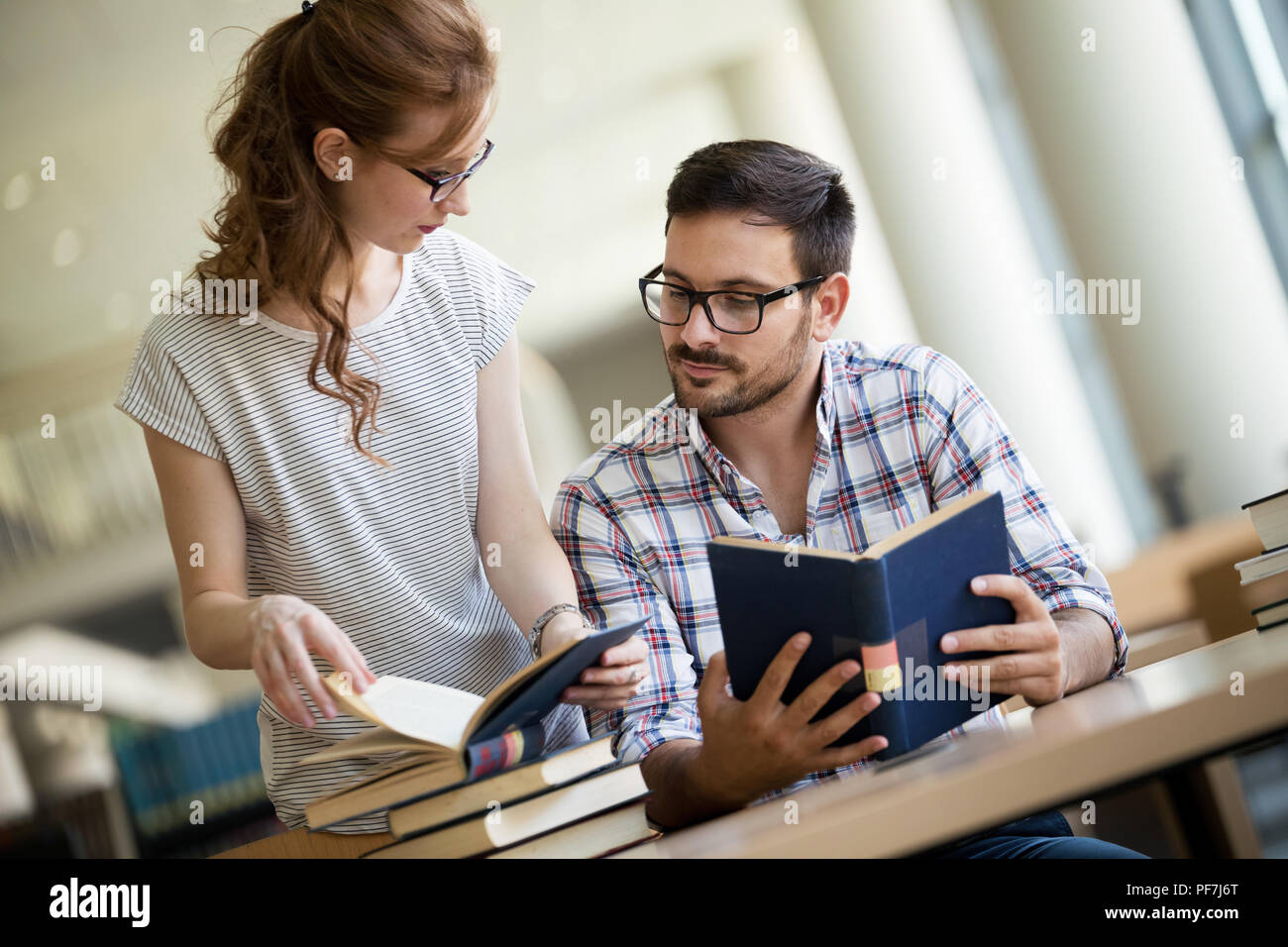 Young happy students sitting in library Stock Photo - Alamy