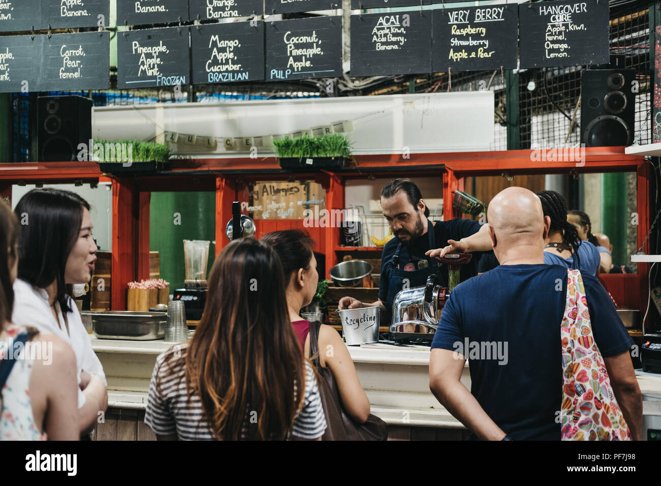London, UK - July 24, 2018: People queuing to buy fresh juice while man ...