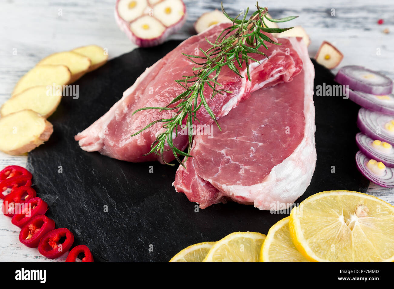 Raw pork meat on black slate plate with spice ingredient - rosemary ...