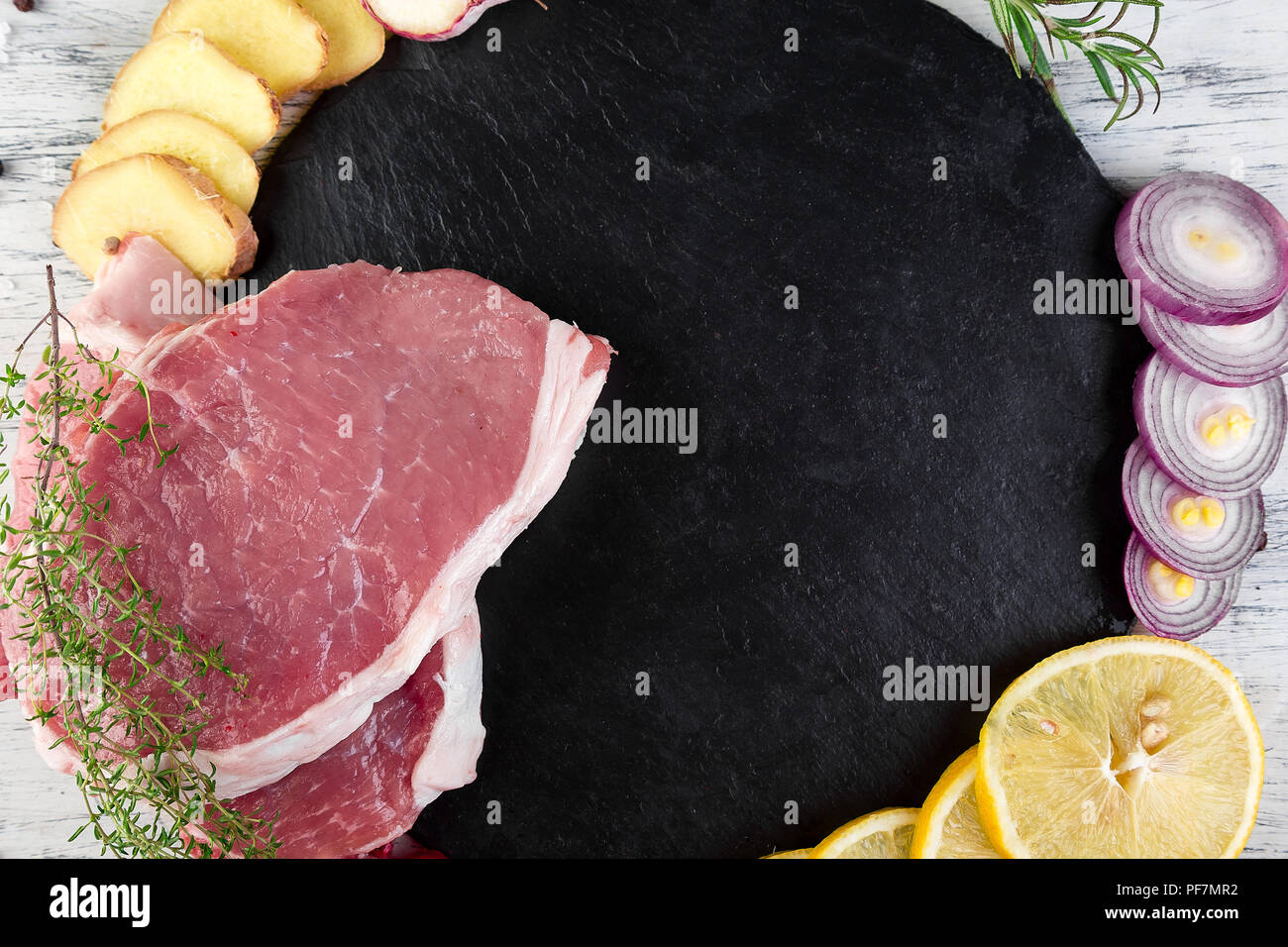 Raw pork meat on black slate plate with spice ingredient - rosemary ...
