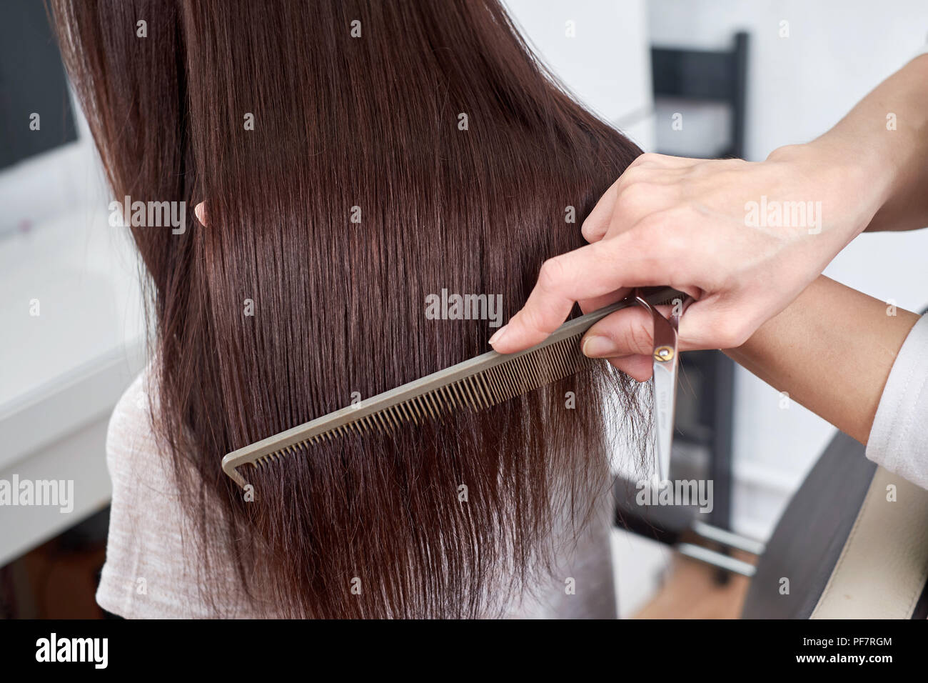 Closeup hairdresser makes hairstyle for young woman in beauty salon ...