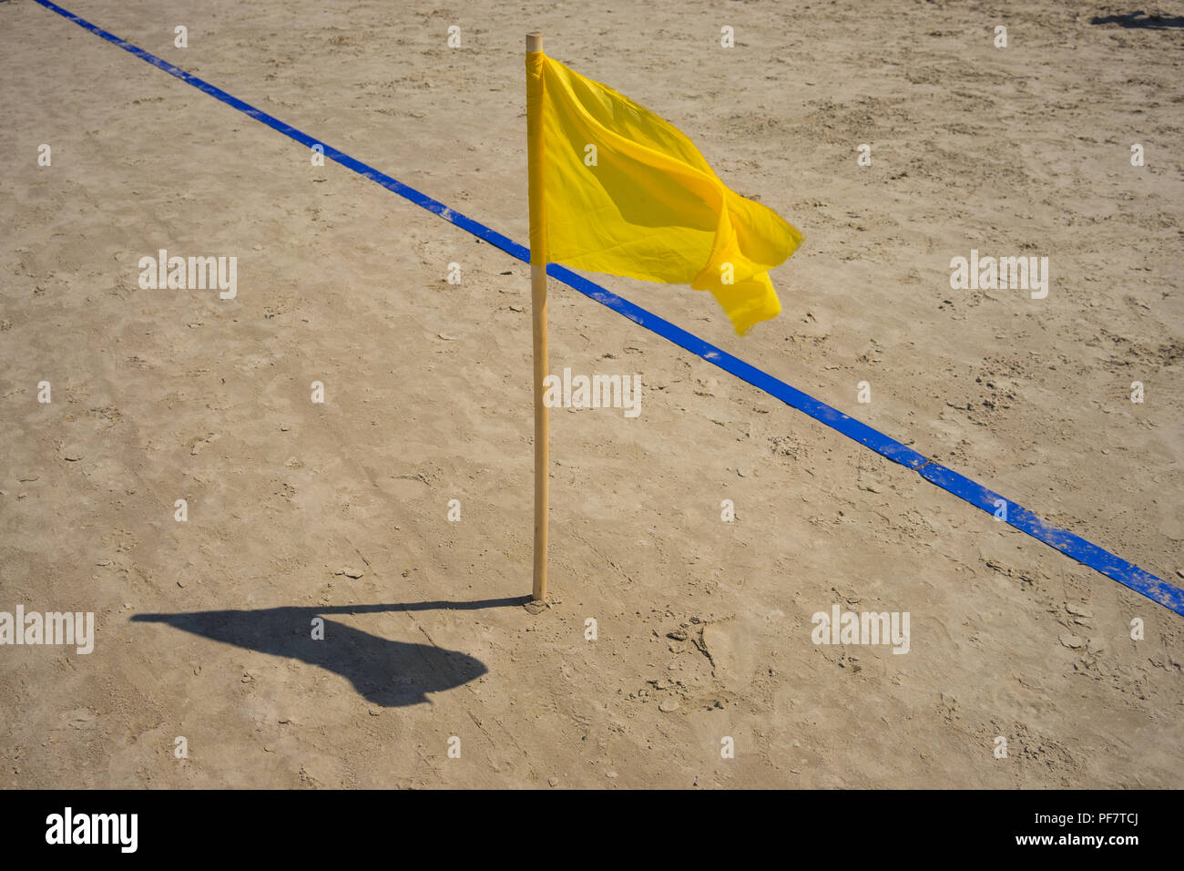 Yellow flag and the blue line on the golden sand beach Stock Photo - Alamy