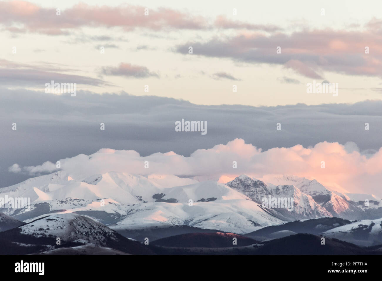 Mountain range covered by snow at sunset, with warm, purple shades ...