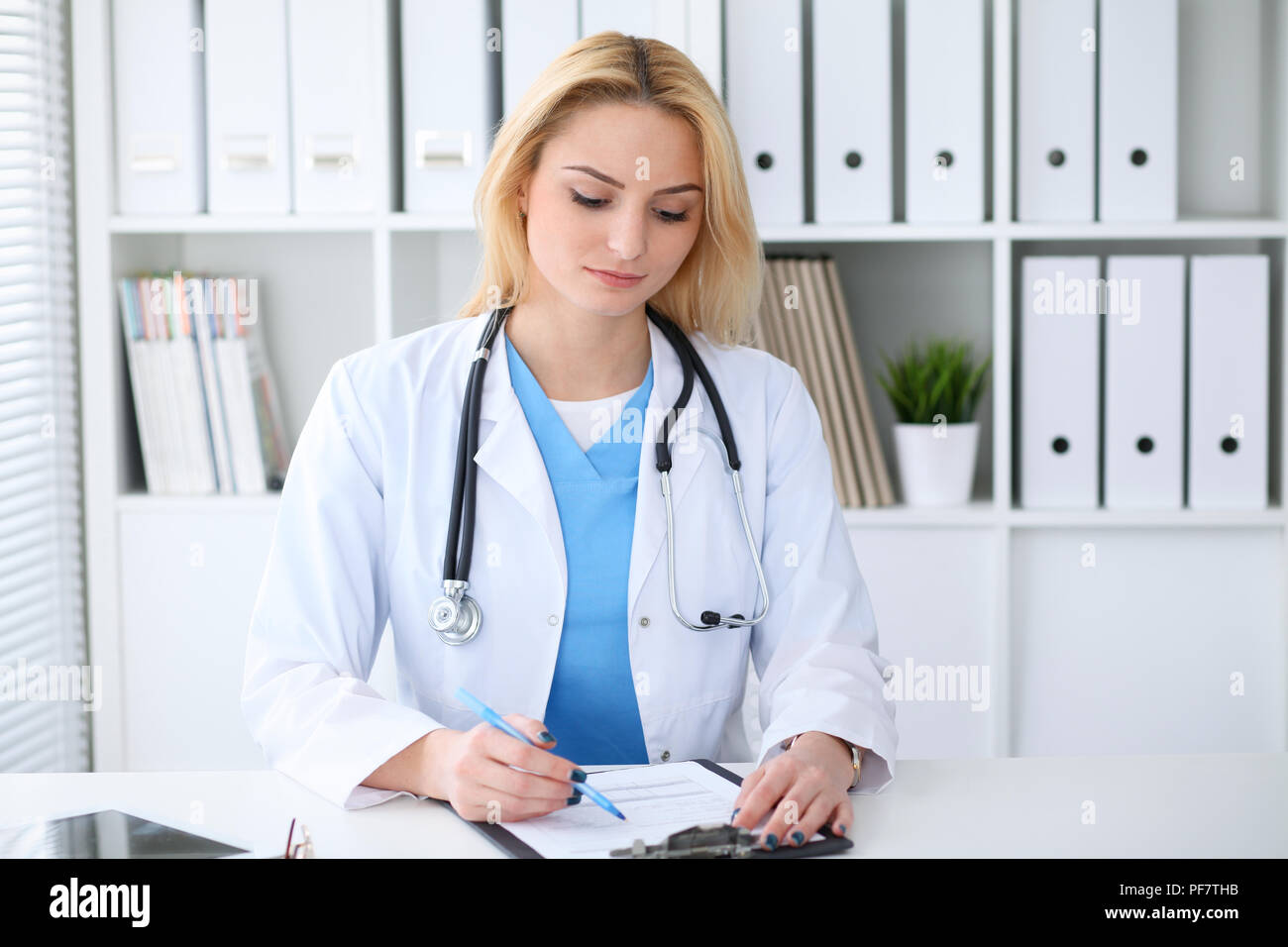 Doctor woman at work. Portrait of cheerful smiling blonde physician ...