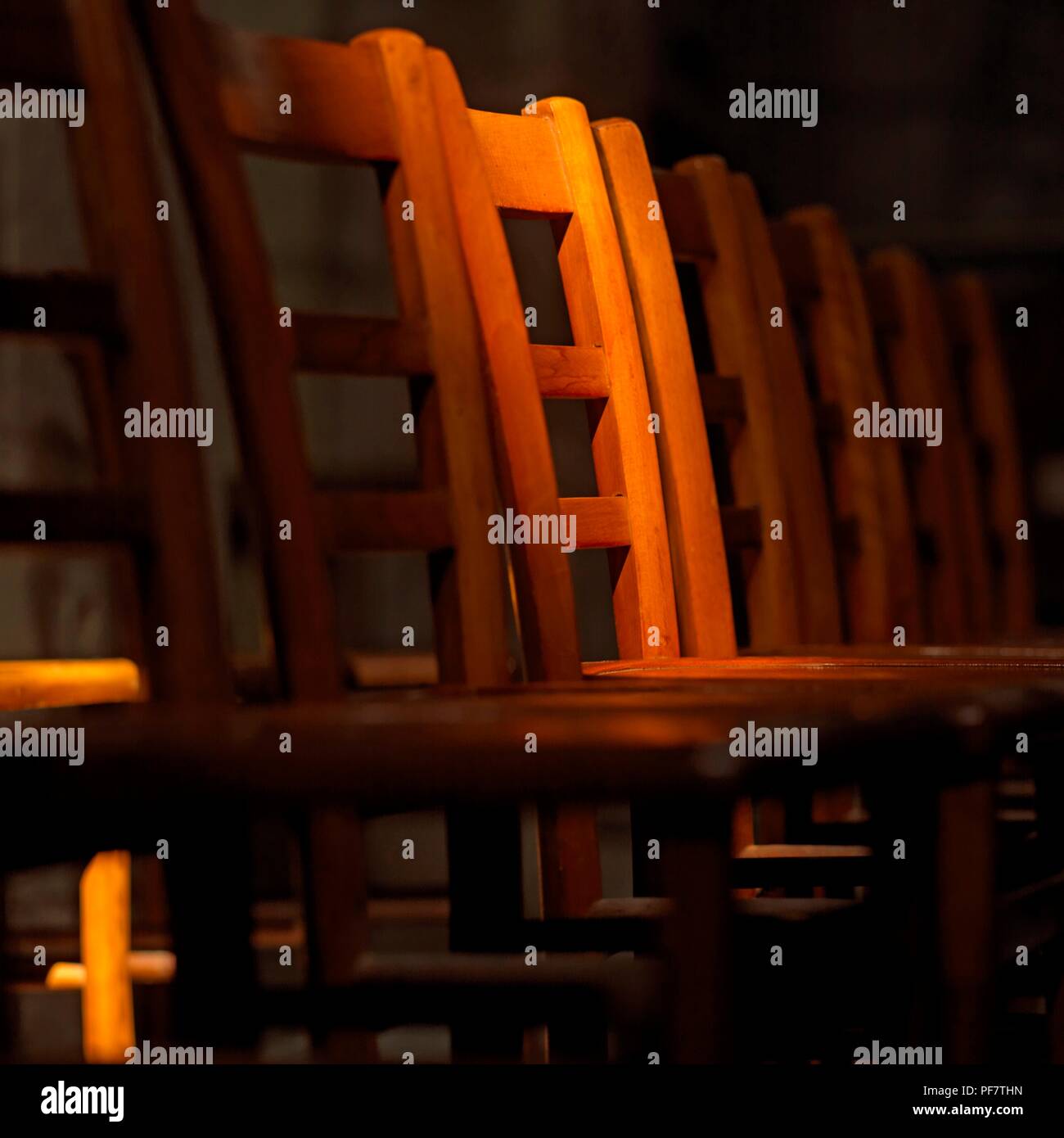 Closeup shot of chairs put in a row under an orange light Stock Photo ...