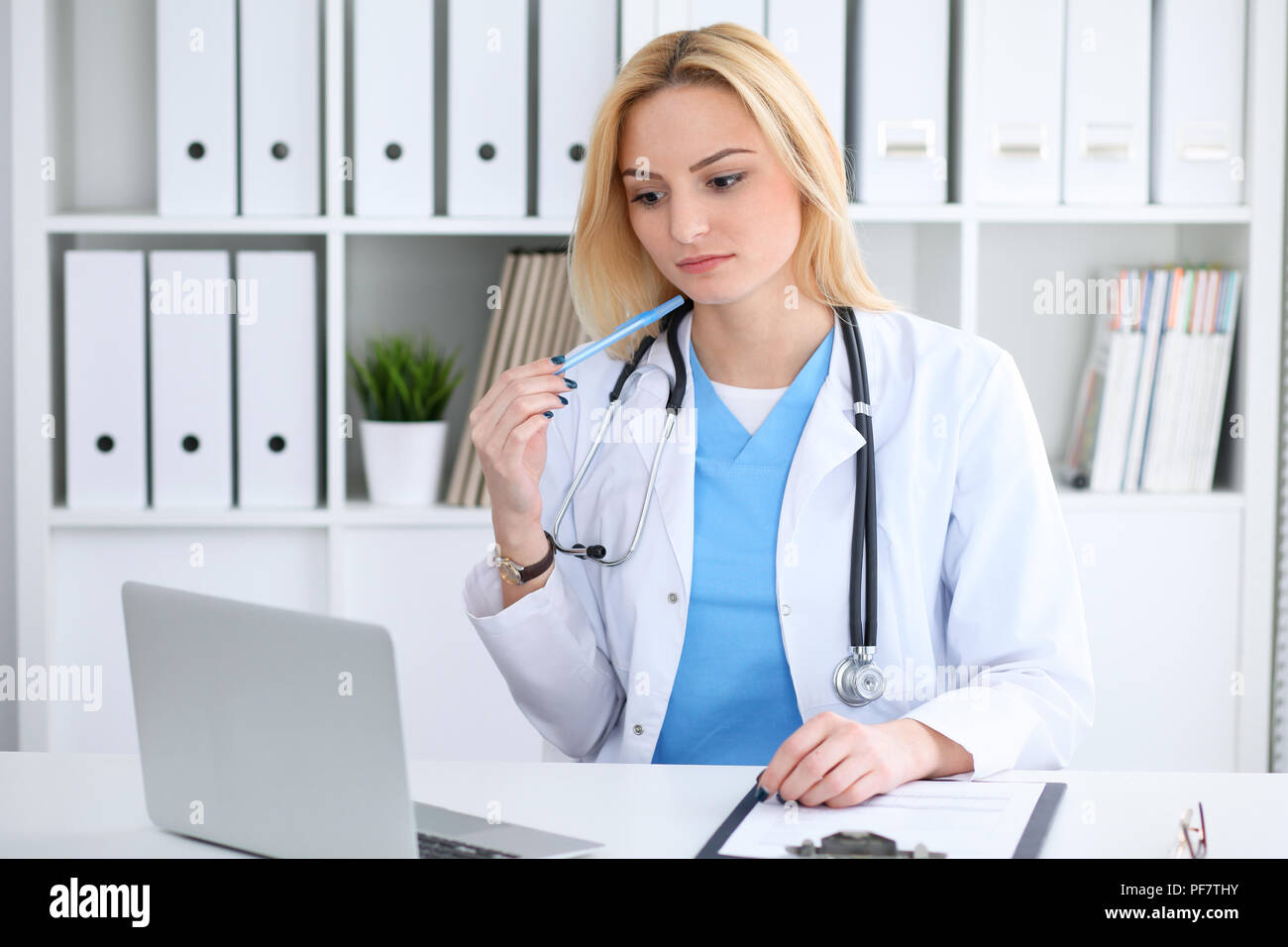 Doctor woman at work. Portrait of cheerful smiling blonde physician ...