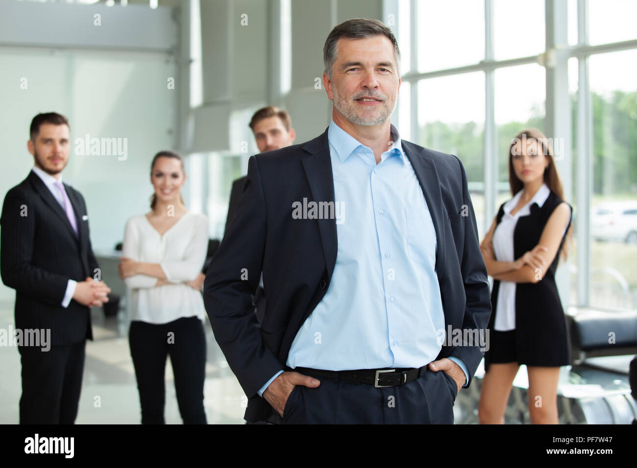 Mature smiling business manager crossing his arms in front of his ...