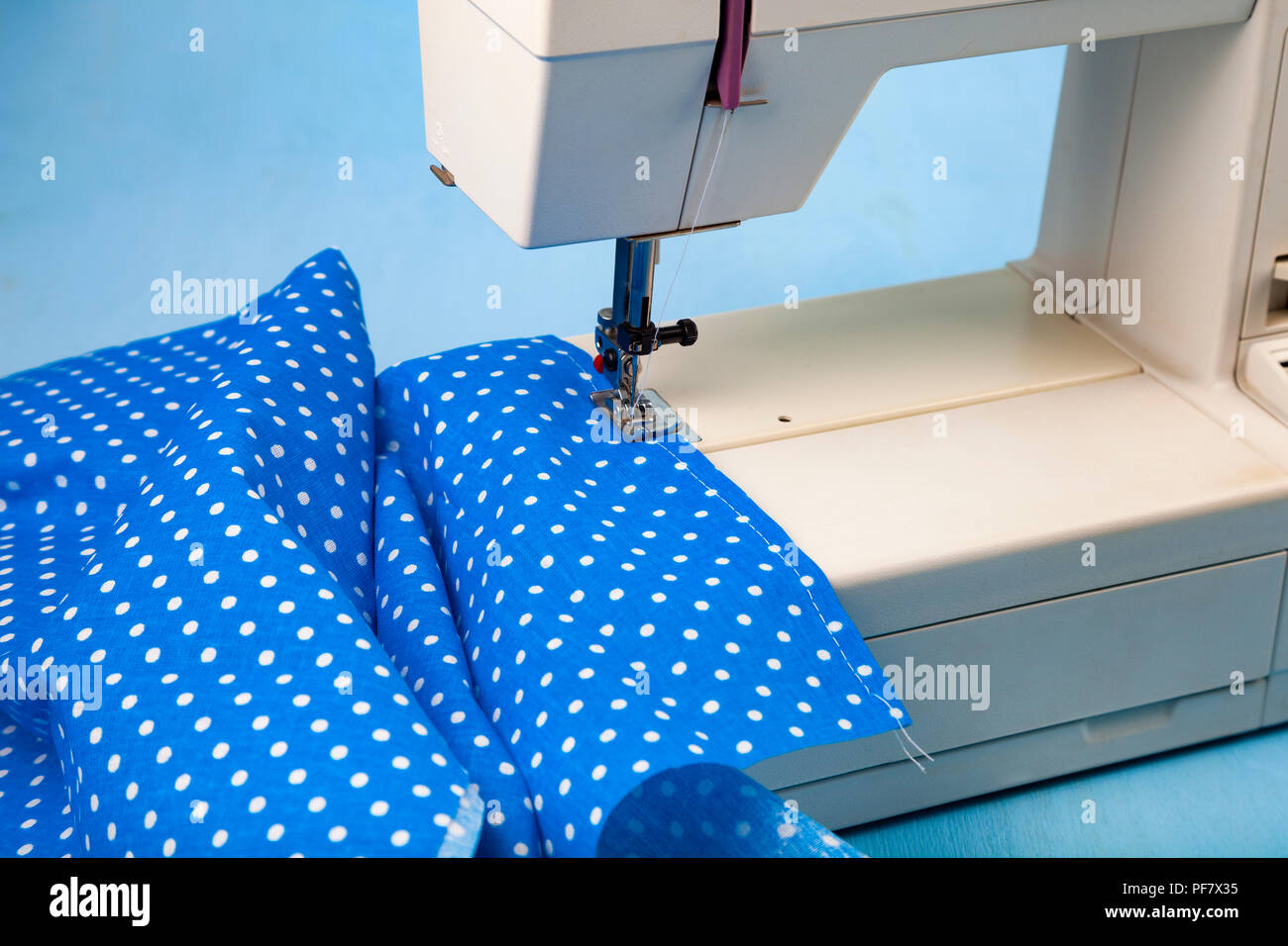 Sewing machine and blue fabric close-up Stock Photo - Alamy