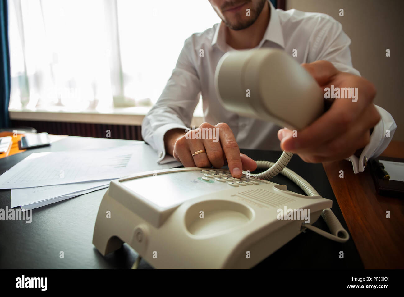 Businessman dialing a telephone number in order to make a phone call ...