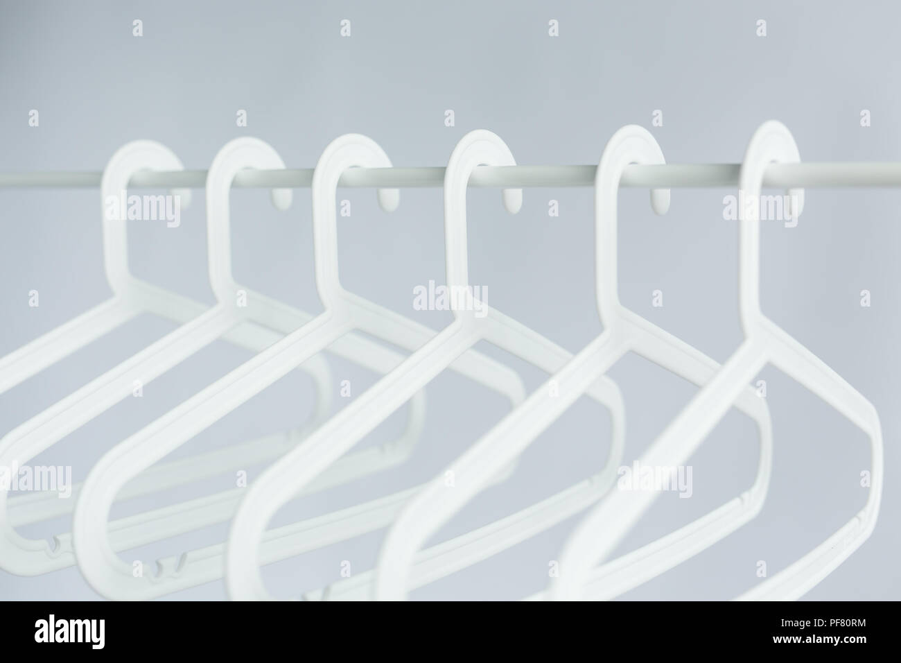 clothing, costume and accessories concept - plastic hangers on a rod on ...