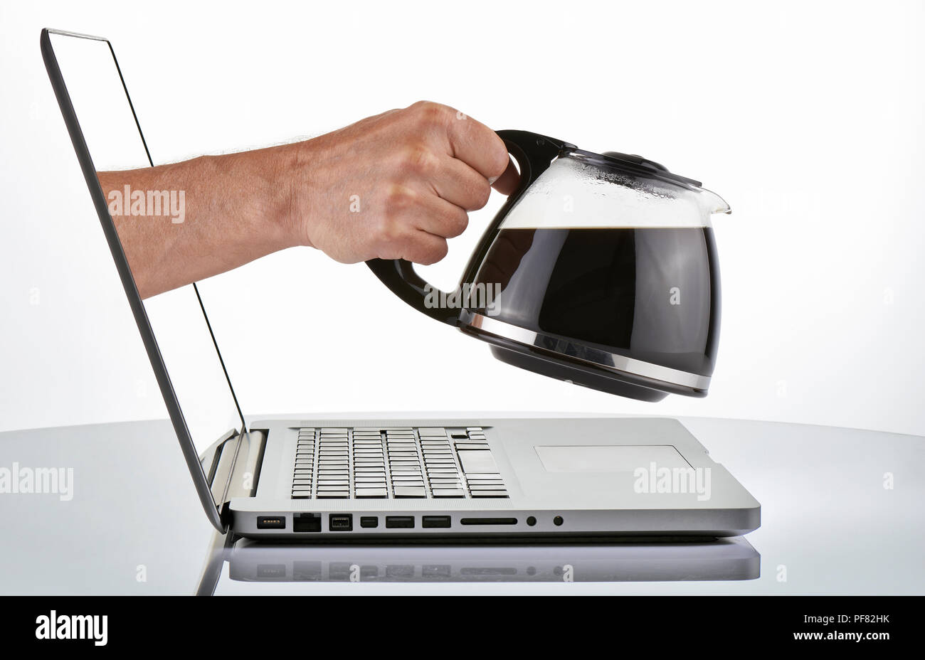 laptop with man's hand holding and pouring coffee into a brown cup ...