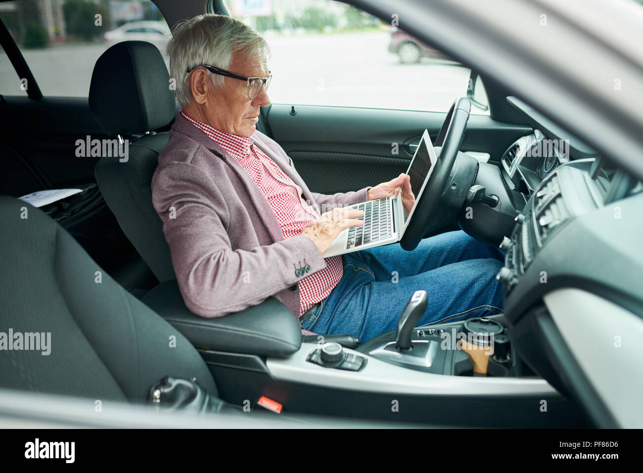 Senior Businessman Using Laptop in Car Stock Photo - Alamy