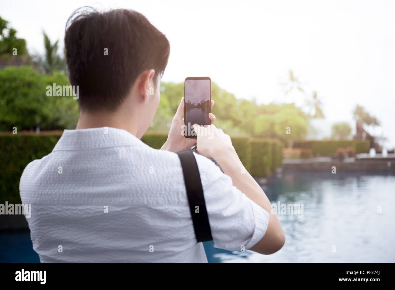 Young man tourist taking photos of landscape with cell phone on ...