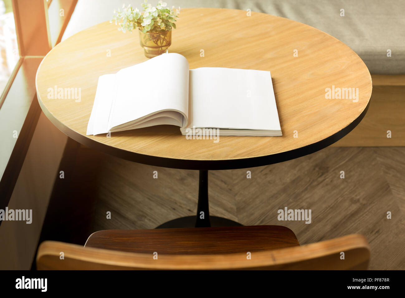 Wooden table with an opened book and plant on window with sunlight ...
