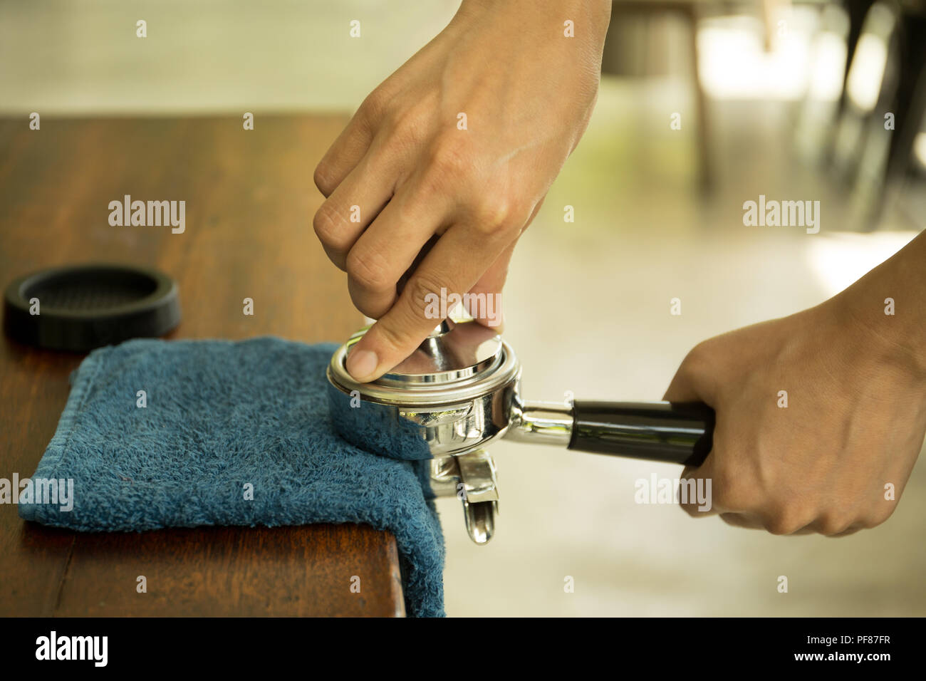 Barista pressing ground coffee into portafilter using tamper with blue ...
