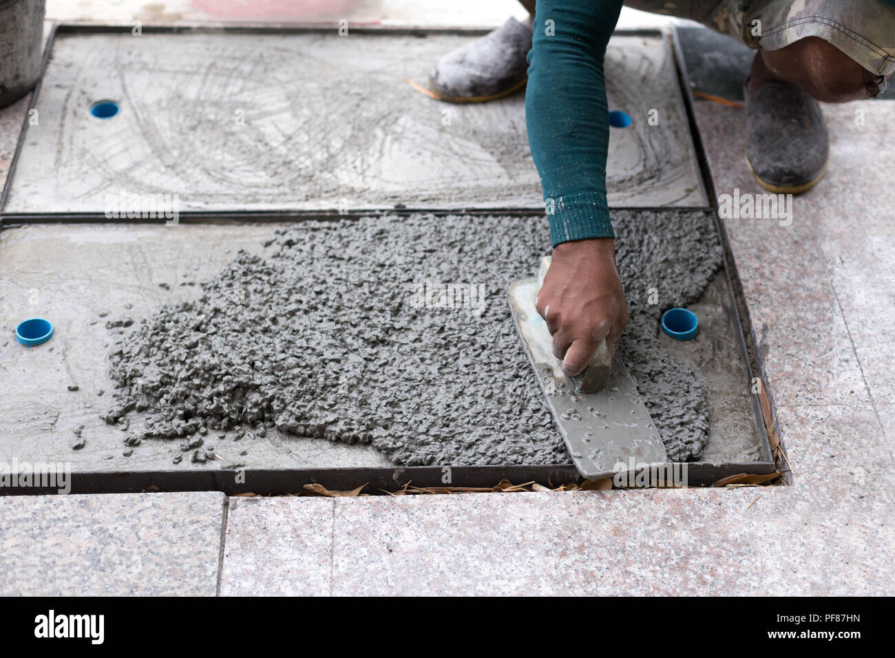 Worker leveling cement of drain hose with trowel in construction site ...