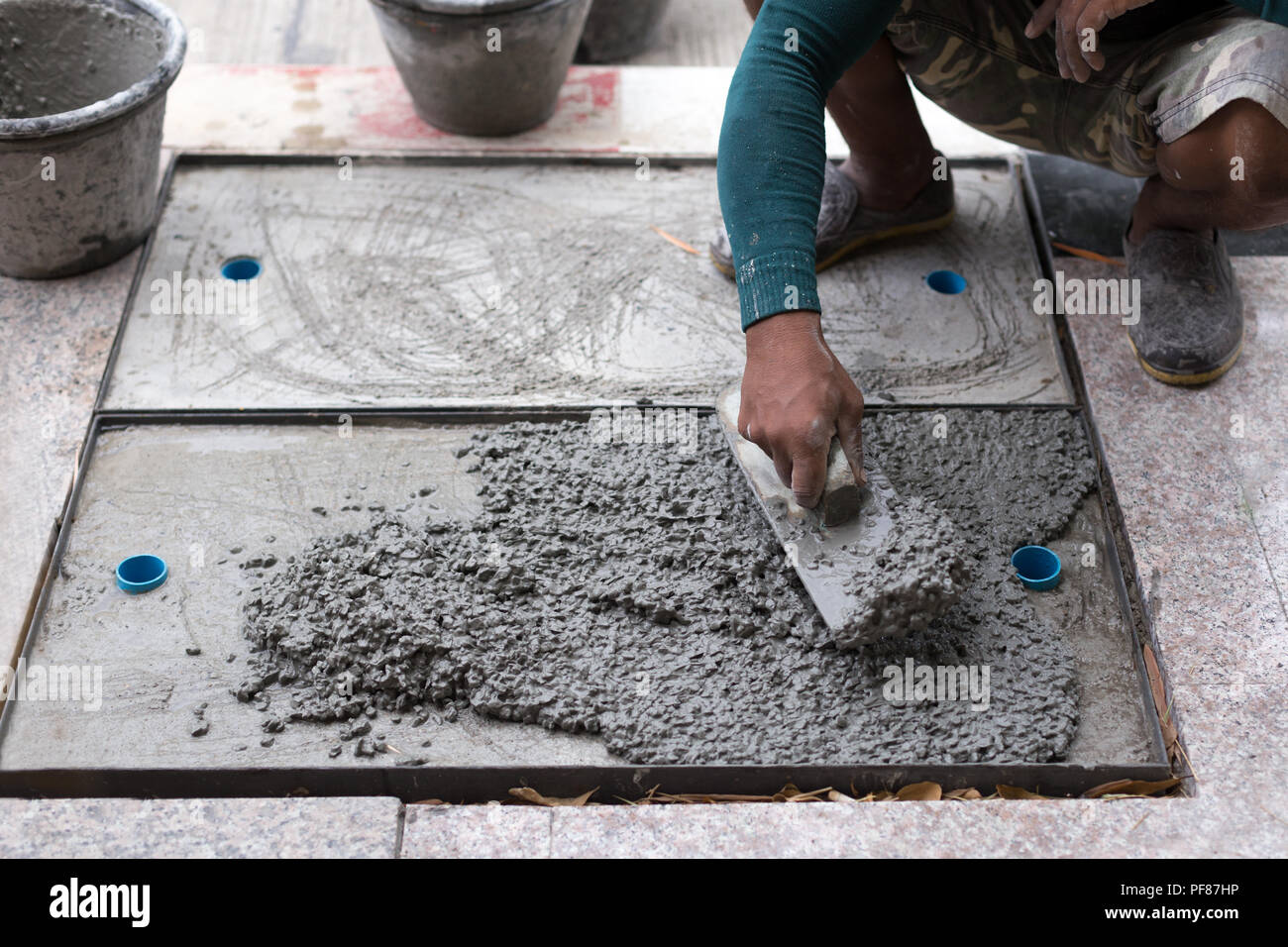 Worker leveling cement of drain hose with trowel in construction site ...