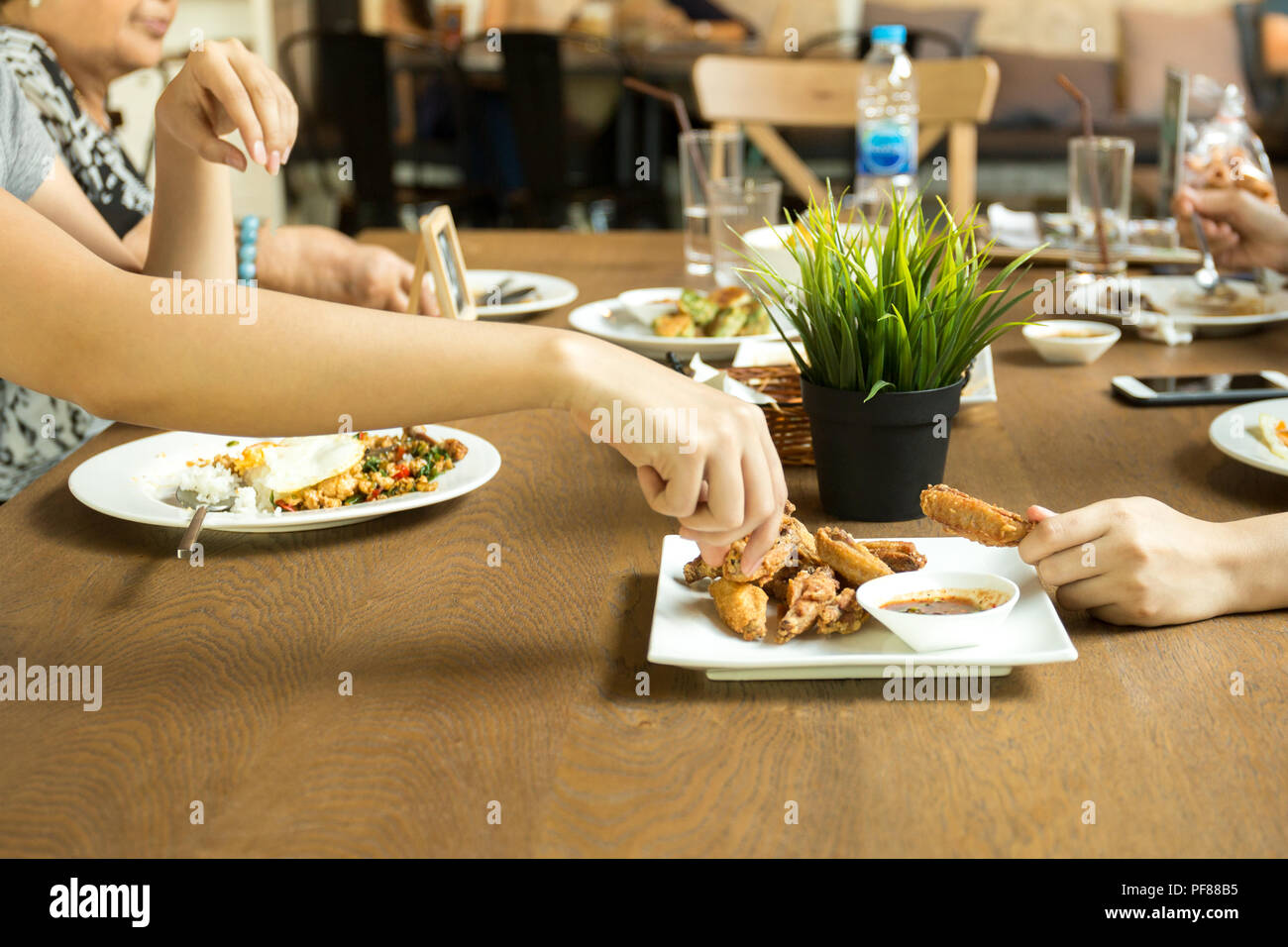 Happy family enjoying good time female hand holding chicken wing at ...