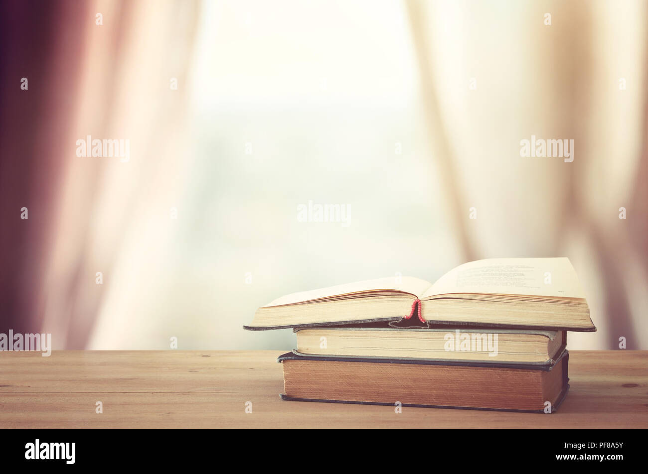 back to school concept. stack of books over wooden desk in front of day ...
