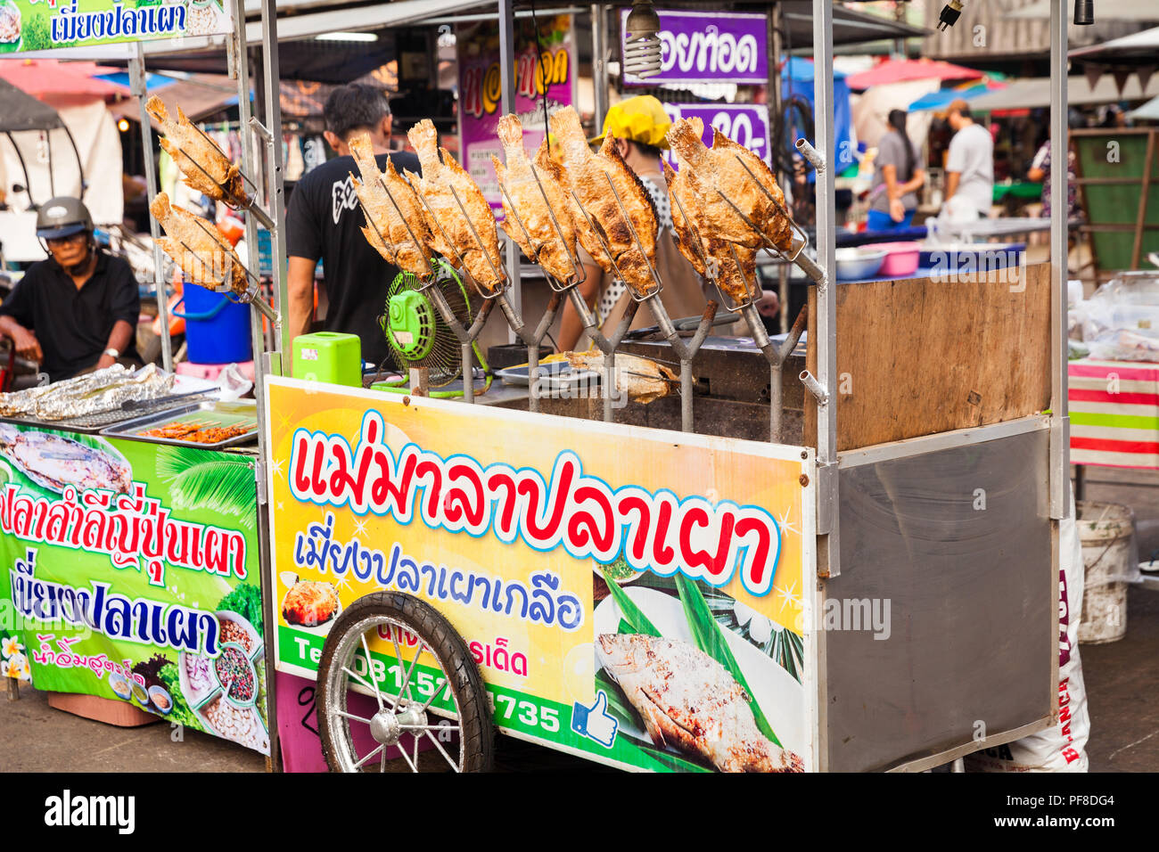 Enthusiastic street cook prepares a delicious chicken in outdoor market ...
