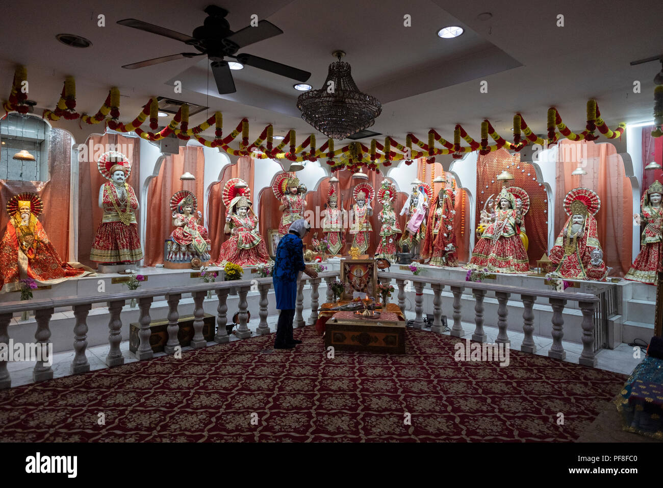 A Hindu woman prays and meditates in front of statues of deities at the ...