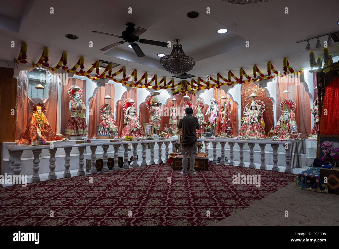 A Hindu couple pray and meditate in front of statues of deities at the ...